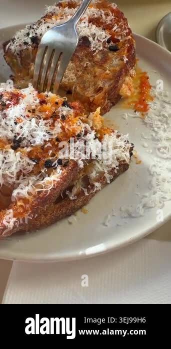 White woman at brunch tasting parmesan toast, fork lifting bite, pearl ...