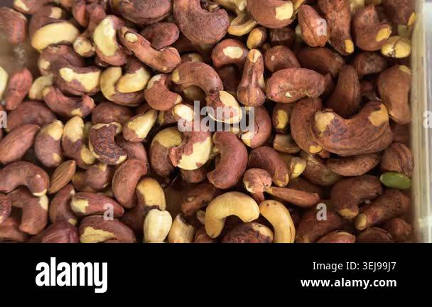 Whole roasted cashew nuts in hard shells displayed in container with ...