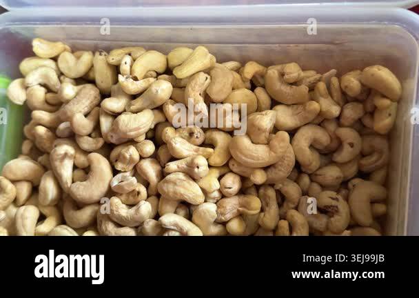 Fresh unroasted cashew nuts displayed in container with smooth natural ...