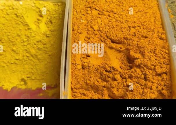 Golden turmeric and vivid orange spices displayed in containers with ...