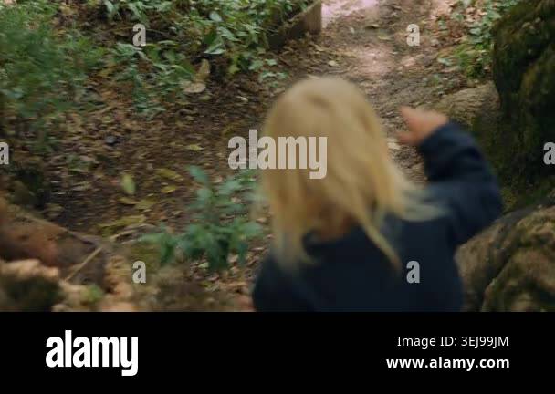 Bold caucasian toddler points and walks down shaded trail, confident ...