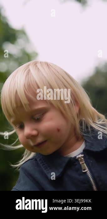Happy toddler spinning and reaching with stick, lively expression and ...