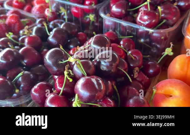 Fresh sweet cherries in transparent plastic containers at local market ...