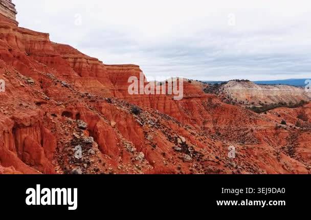 Red clay badlands and eroded canyons under a cloudy sky. Wide landscape ...