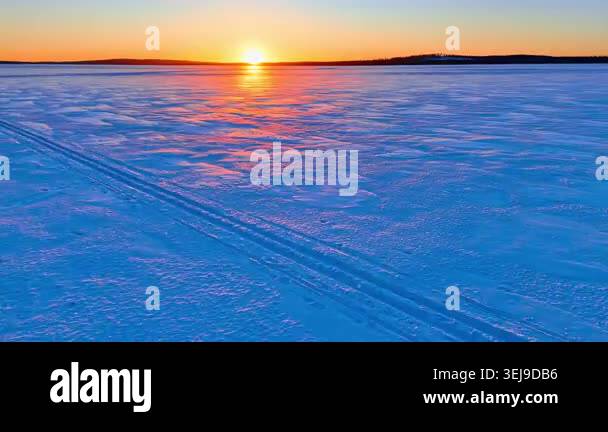 Moving fast over the snowy valley at sundown. Setting sun colors the ...