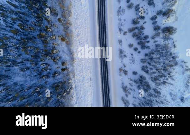 Cars move by the motorway crossing the snowy nature landscape. Scarce ...