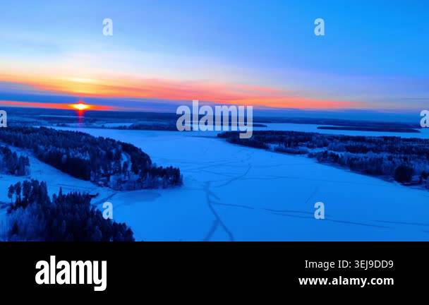 Large fields covered with snow and surrounded by woods. Setting sun in ...