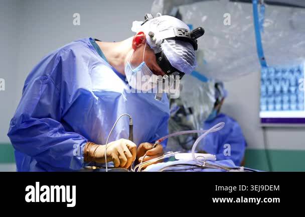 Male surgeon equipped with surgical loupes works at operation. Doctor ...