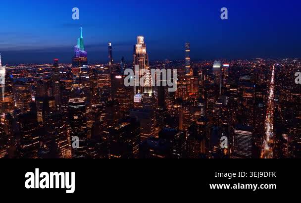 Manhattan skyscrapers lit by neon light against dark blue sky. Jaw ...