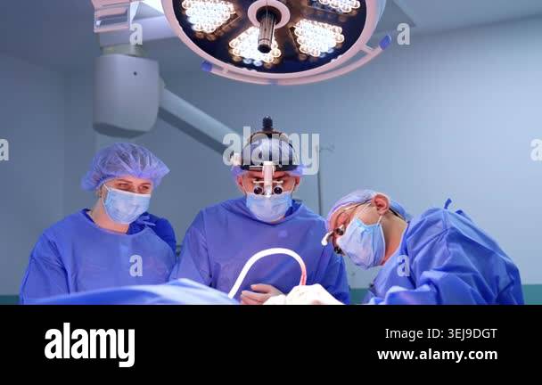 Team of doctors in blue robes working in modern surgery room ...