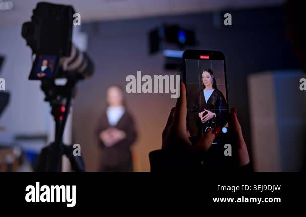 Female hands hold a phone taking video of a beautiful brunette lady ...