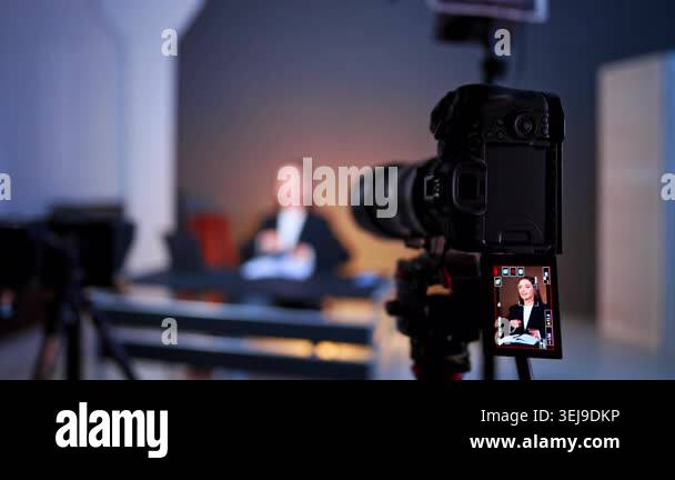 Professional camera taking video of a beautiful woman sitting at desk ...