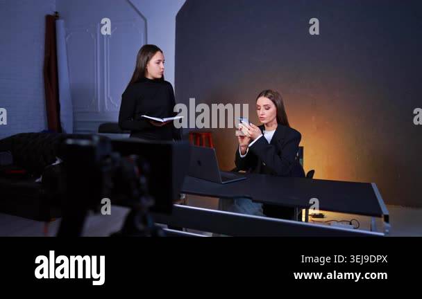 Lady wearing black jacket sits at desk looking at her phone. Young ...