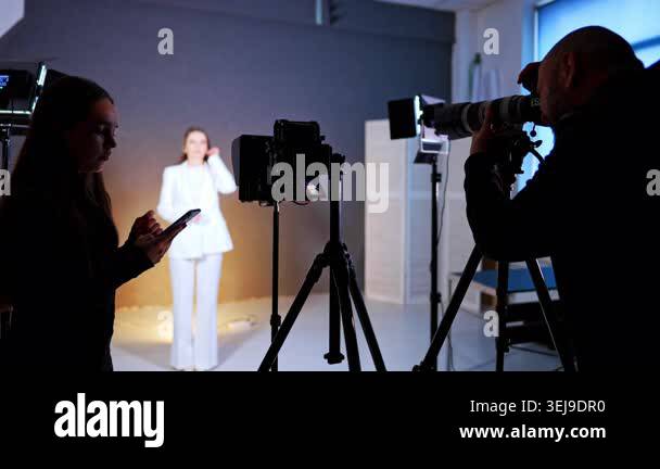 Photographer is taking pictures of a woman in white suit. Long-haired ...