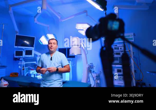 Doctor in blue uniform talks to camera set in surgery room. Medical ...