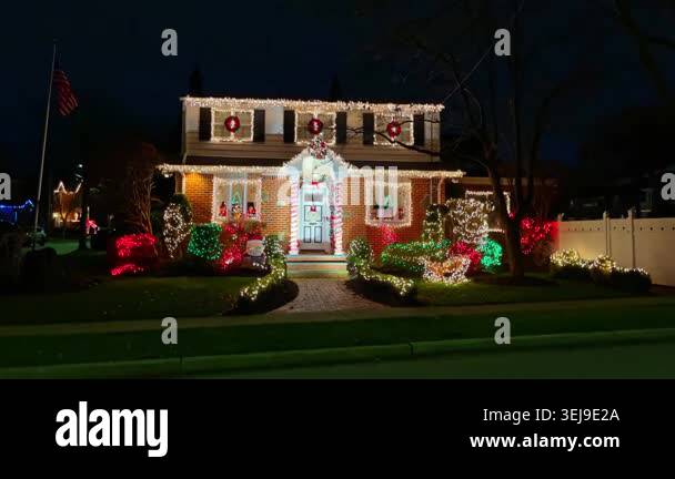 Colorful light garlands decorate the house facade and bushes growing by ...