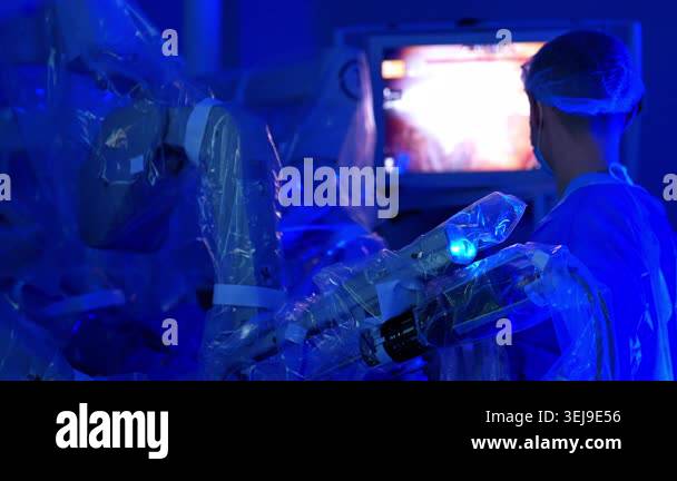 Male medic stands at the robotic surgeon system. Doctor looks at the ...