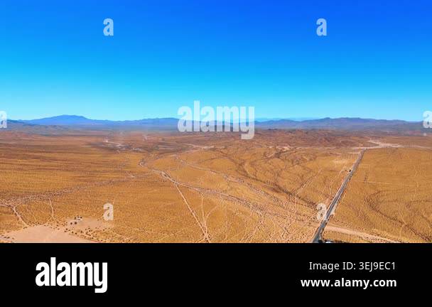 Vast deserted landscape against blue clear sky. A highway crosses the ...