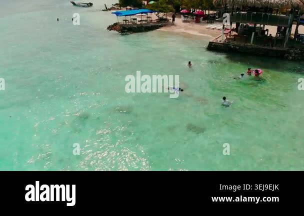Drone diagonal aerial shot of Isla Mucura beach with huts and people ...