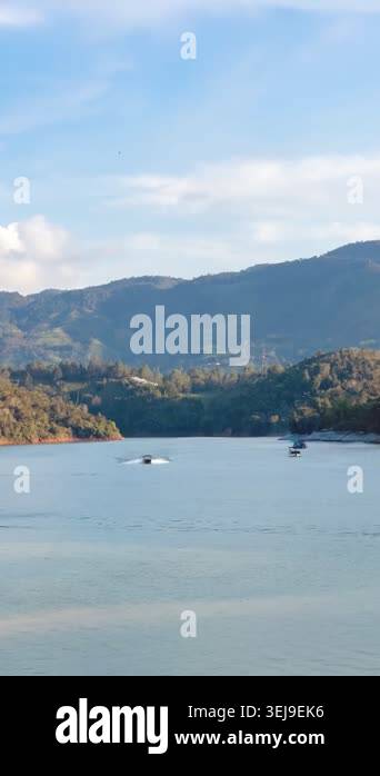 Vertical video of Guatape reservoir with distant boats sailing slowly ...