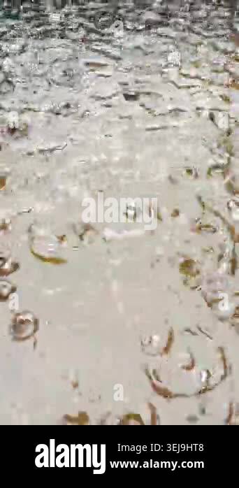 Rain drops and hail stones falling into a pool of waste water. High ...