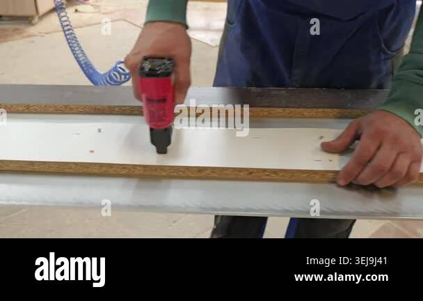 Close up view of a professional carpenter using a pneumatic nail gun to ...
