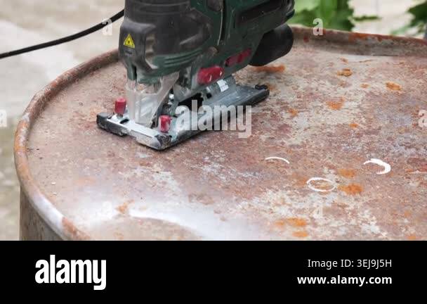 Jigsaw with a sharp blade precisely cutting a hole in the rusty top of ...