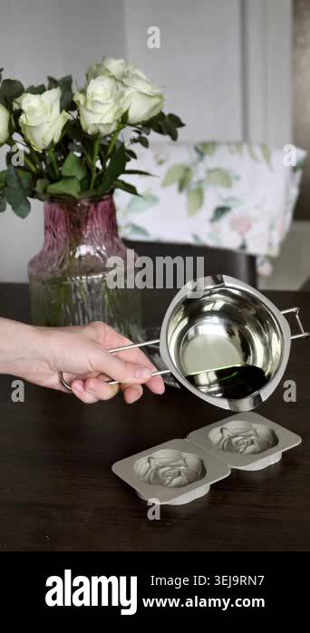 Close up of a woman pouring liquid green wax into a rose-shaped ...