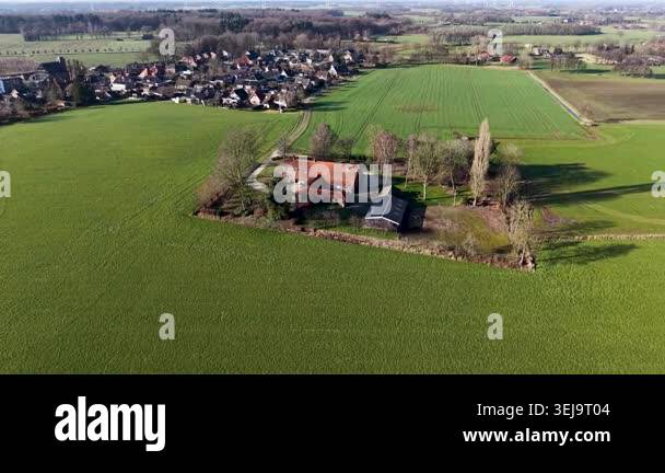 An aerial view shows a traditional brick farmhouse nestled among trees ...