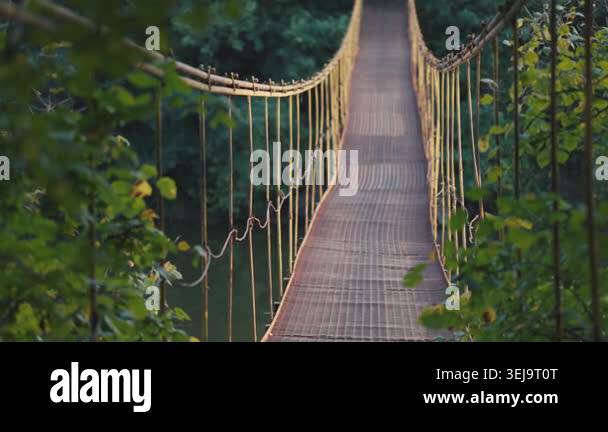 A long suspension footbridge made of metal mesh stretches across a ...