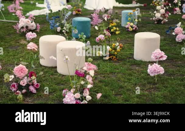 Wedding seating setup with elegant poufs and flower decor on grass for ...