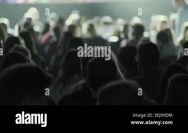 Rear view of crowded audience in dim venue, people watching live ...