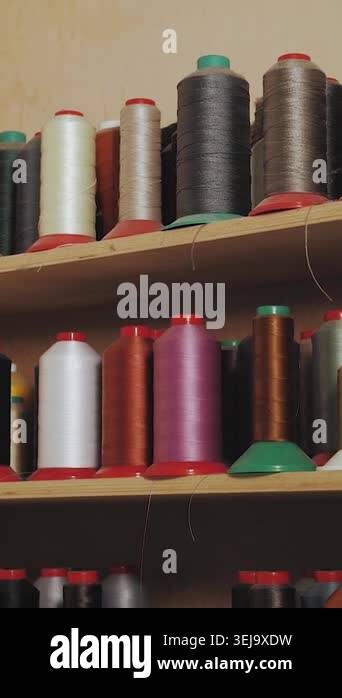 Vertical video. Colorful thread spools arranged on wooden shelves in ...
