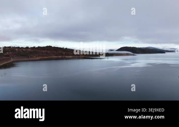 Aerial video showcasing the Glenbawn Dam wall surrounded by a foggy ...