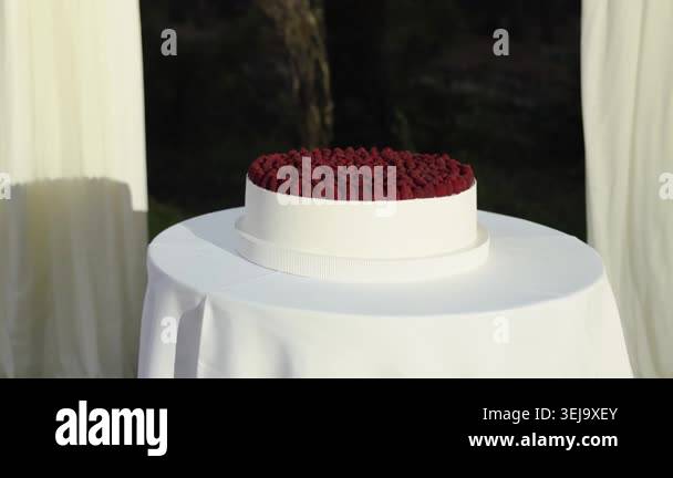 Wedding cake with fresh raspberries on top standing on table for ...