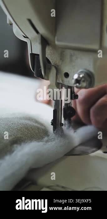 Vertical video. Close-up view of industrial sewing machine working with ...