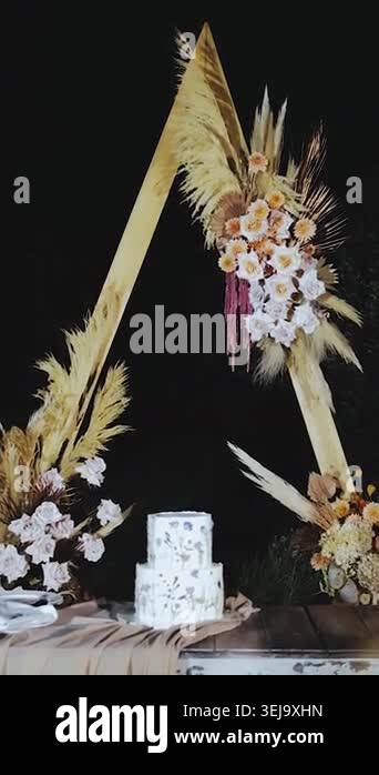 Vertical video. Luxury outdoor wedding setup with geometric wooden arch ...