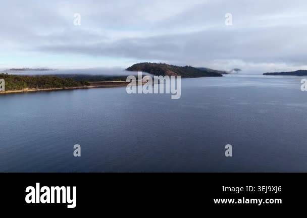 Aerial video showcasing the Glenbawn Dam wall surrounded by a foggy ...