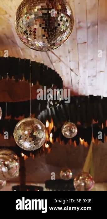 Vertical video. Hanging disco mirror balls with warm decorative lights ...