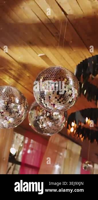 Vertical video. Hanging disco mirror balls with decorative party lights ...