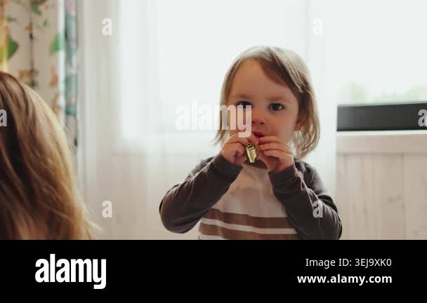 Cute toddler blowing party horn while playing in cozy room at home with ...