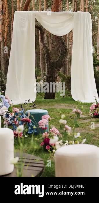 Vertical video. Outdoor wedding ceremony with white fabric arch and ...