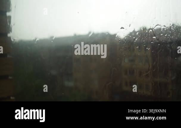 Rain falls on window glass covered with a mosquito net. Peering through ...