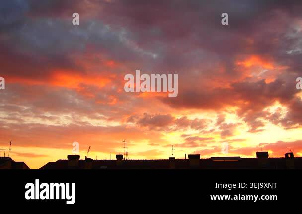 Bright colors fill the sky as the sun sets behind the city buildings ...