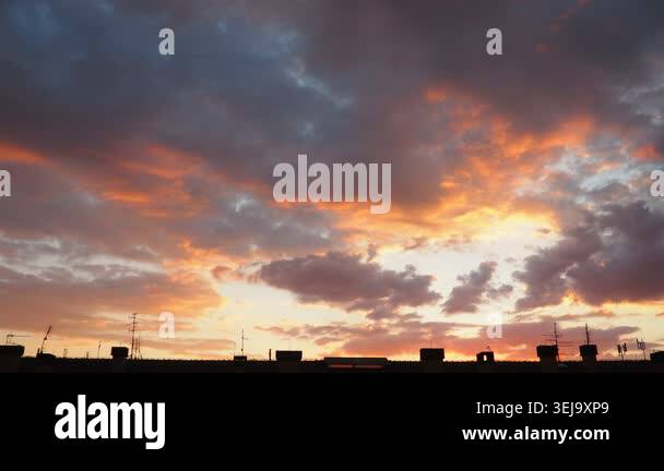 A sunset unfolds over a city skyline with orange, pink, and purple ...