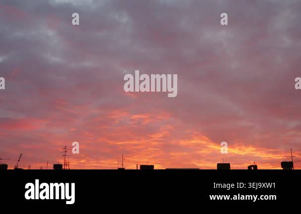 The sky glows in bright colors as the sun sets over the city. The ...