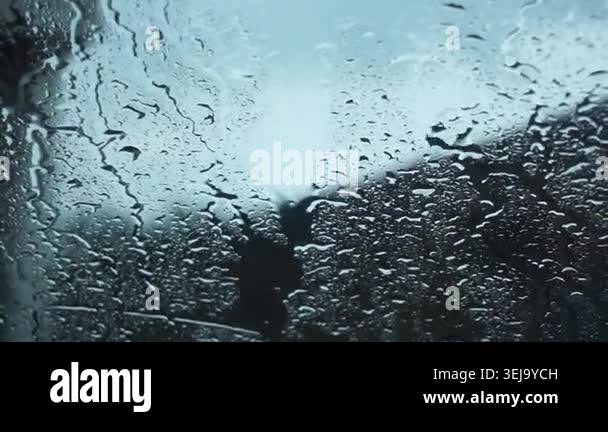 Raindrops sliding down a windowpane with a blurry view of a house Stock ...