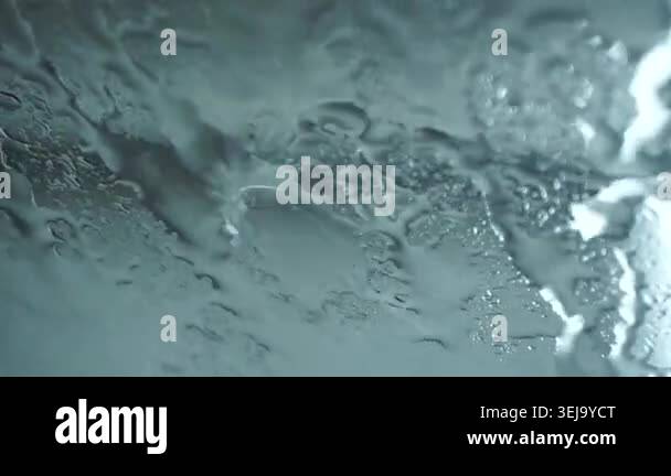 Heavy rainwater flowing heavily down a glass surface with abstract ...