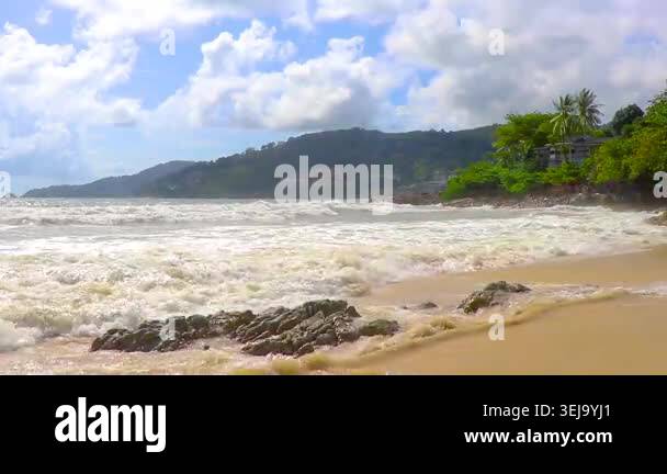 Turquoise ocean wave crashing on rocks at Kalim Beach Phuket in wide ...