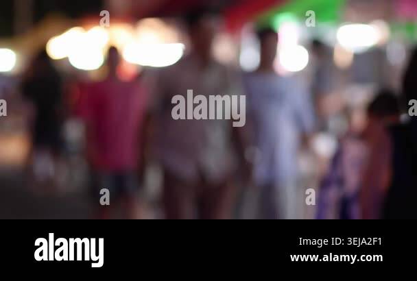 Blurred crowd walking in a night market with colorful bokeh lights and ...